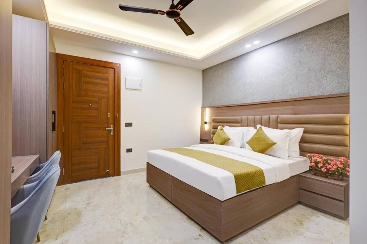Quarto com cama, mesas de cabeceira, guarda-roupa e ventoinha no teto.