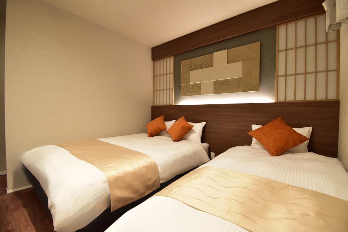 Quarto de hotel com duas camas, uma cabeceira de madeira e um painel decorativo na parede.