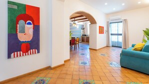 Um interior moderno com área de jantar, sala de estar com sofá e um quadro abstrato colorido na parede.