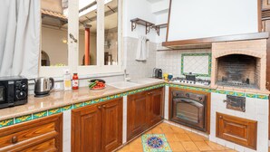 Uma cozinha com armários de madeira, forno embutido, micro-ondas e painel de azulejos.