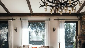 Uma sala de estar espaçosa com um sofá grande, lareira e um candelabro com chifres.