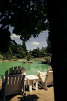 Um deck com cadeiras Adirondack com vista para um corpo d'água calmo, cercado por vegetação.
