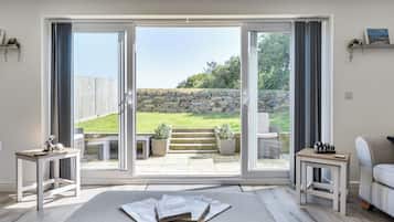 Uma sala de estar moderna com uma grande porta de vidro deslizante que dá para um jardim.