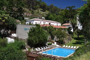 A pool area with lounge chairs and a stone wall.