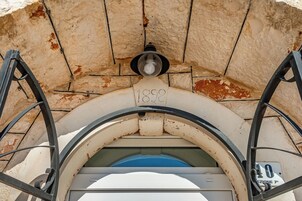 Uma entrada antiga em arco, com uma placa que diz '1898' e um portão de metal.
