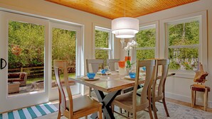 Uma sala de jantar com uma mesa de madeira, cadeiras e um lustre.