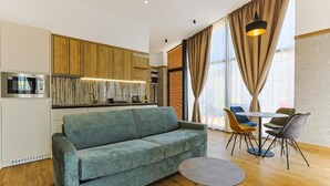 Uma sala de estar moderna com um sofá, uma mesa de centro redonda e um espaço de jantar com cadeiras.