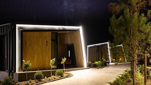 Um edifício moderno com grandes portas de vidro, interior em madeira e fachada bem iluminada.