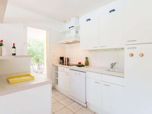 Uma cozinha moderna com armários brancos, uma cafeteira e uma abacaxi no balcão.