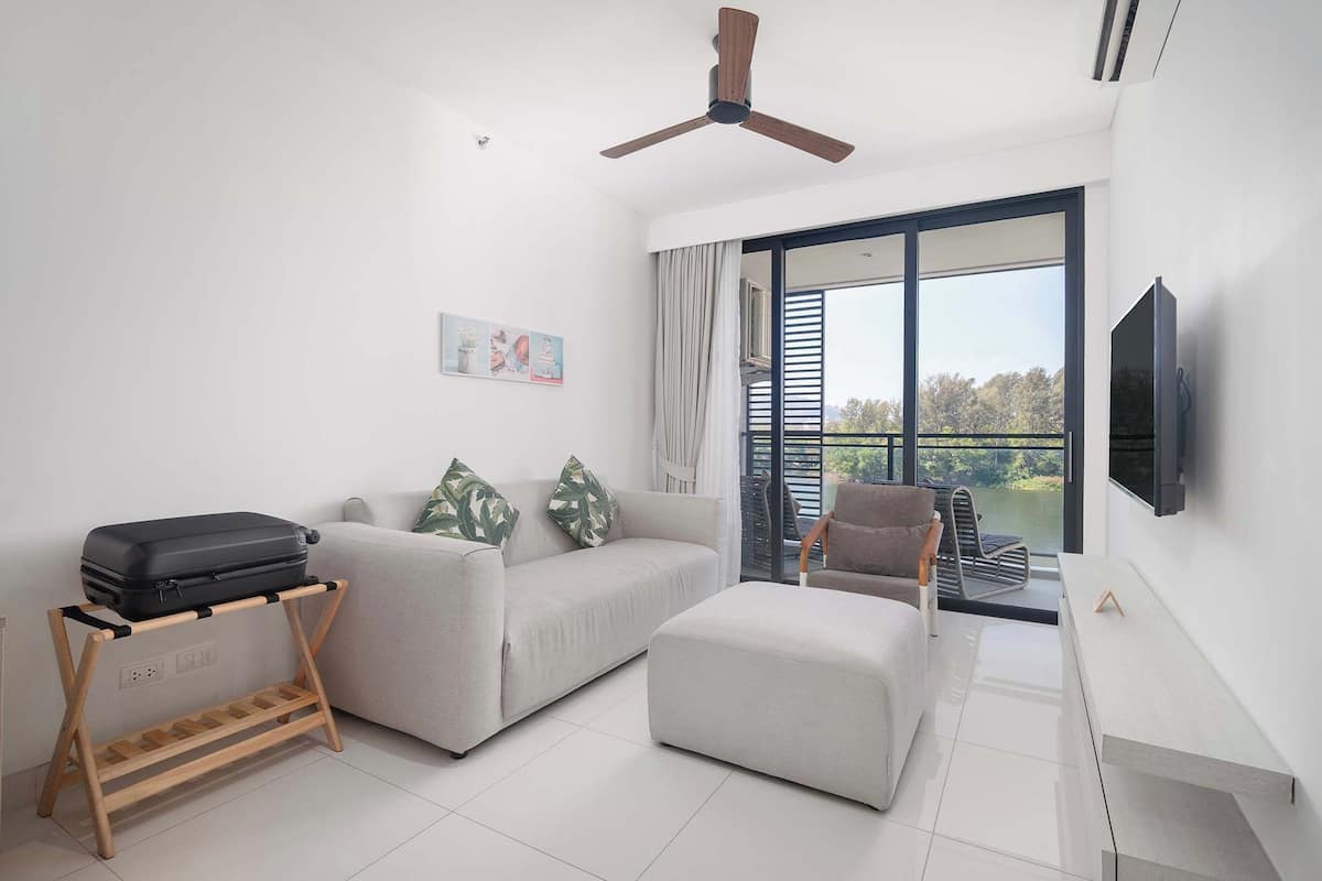 Uma sala de estar moderna com sofá, banqueta e mala sobre um carrinho de madeira.