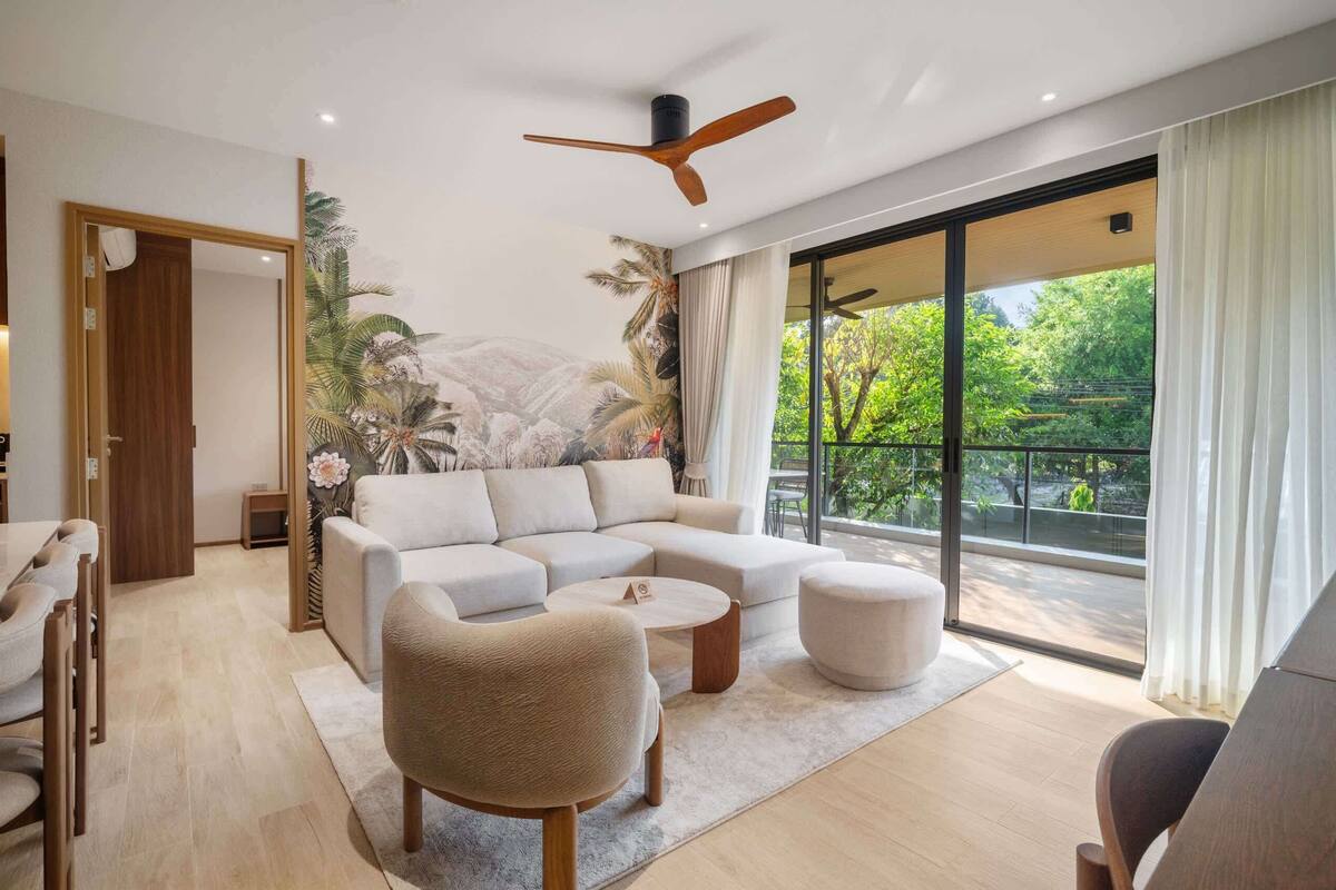 Uma sala de estar moderna com um sofá seccional, uma mesa de centro redonda e um ventilador de teto.