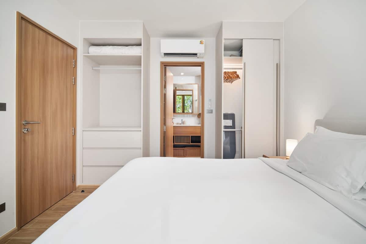 Quarto de hotel com cama, guarda-roupa, espelho e banheiro pequeno.