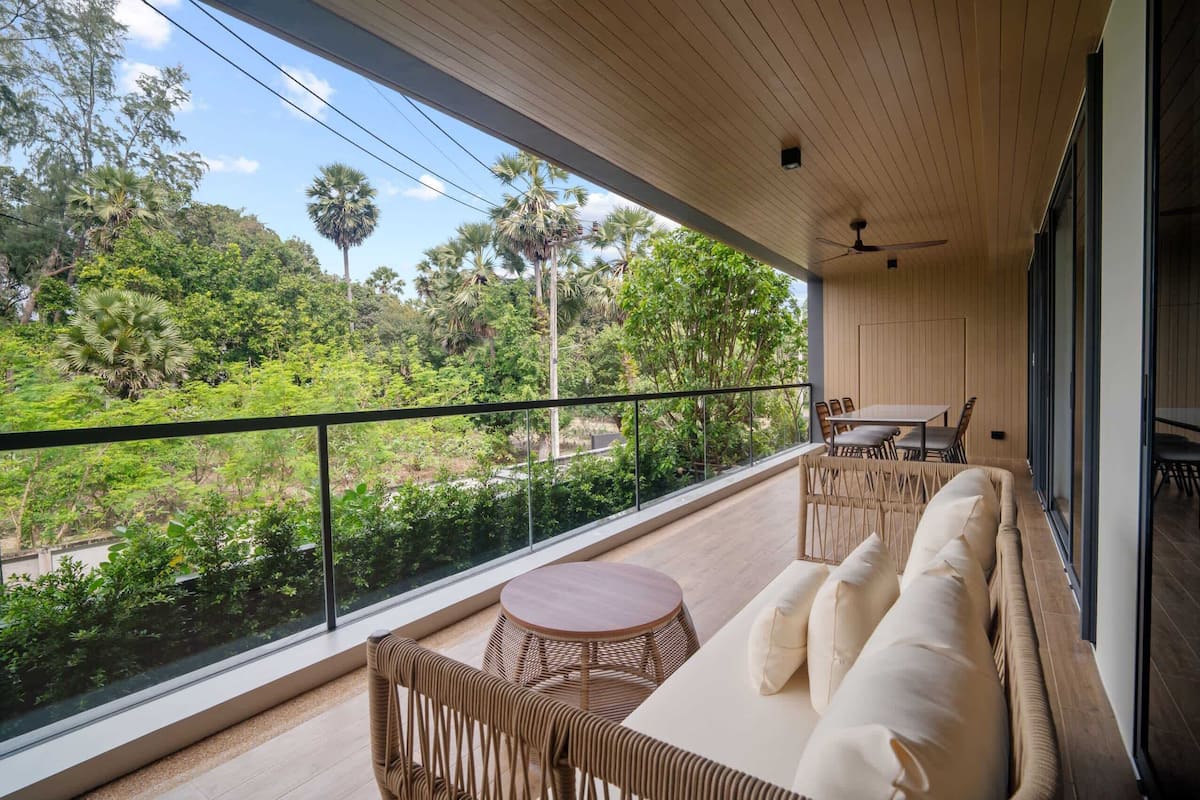 Uma varanda com vista para vegetação exuberante e área de refeições com mesa e cadeiras.
