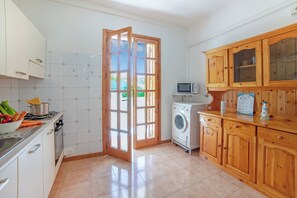 Uma cozinha com fogão, pia, micro-ondas e armários de madeira.