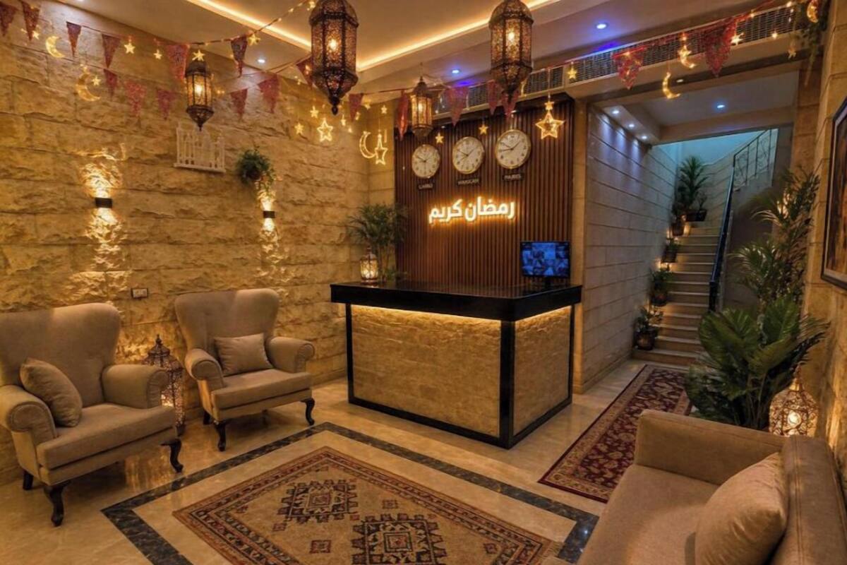 Um hall de entrada com uma mesa de recepção, duas poltronas, um tapete estampado e uma escada.
