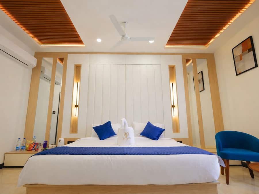 Quarto de hotel com uma cama grande, um ventilador de teto e uma cadeira azul.
