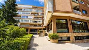 Um edifício residencial com várias andares, varandas, fachada de pedra e céu claro.