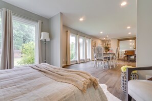 Quarto com cama grande, área de refeições e vista para o verde.