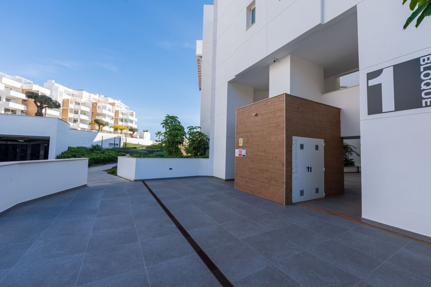 Um edifício moderno com um pátio, estrutura de madeira e uma placa indicando 'BLOCK 1'.