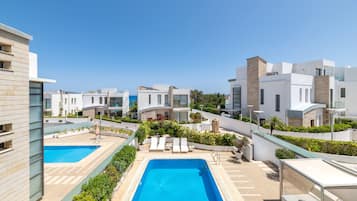 Um hotel moderno com piscina, espreguiçadeiras e um jardim bem cuidado.