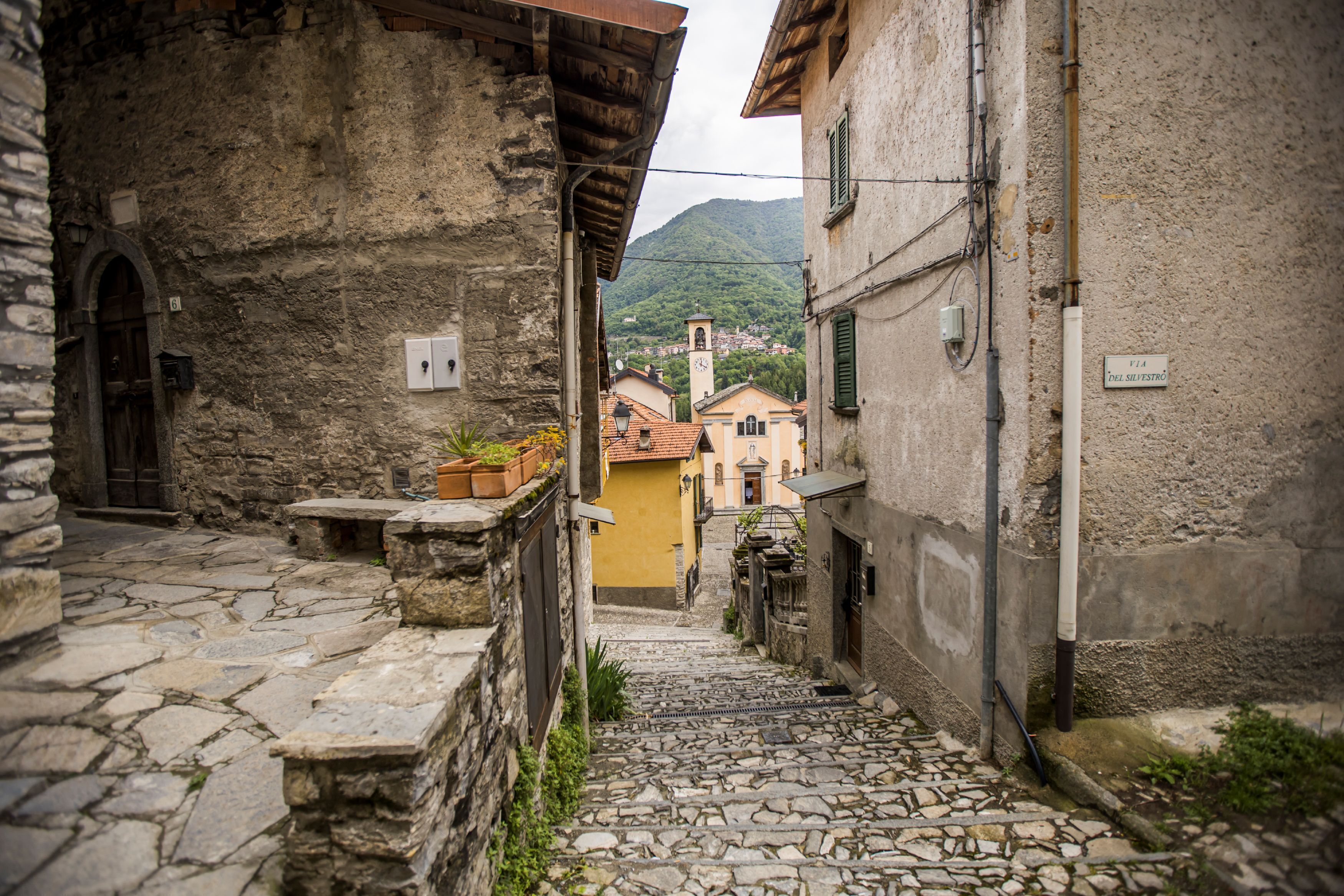 Um caminho de pedra estreito que leva a um edifício com uma porta visível e um pequeno banco.