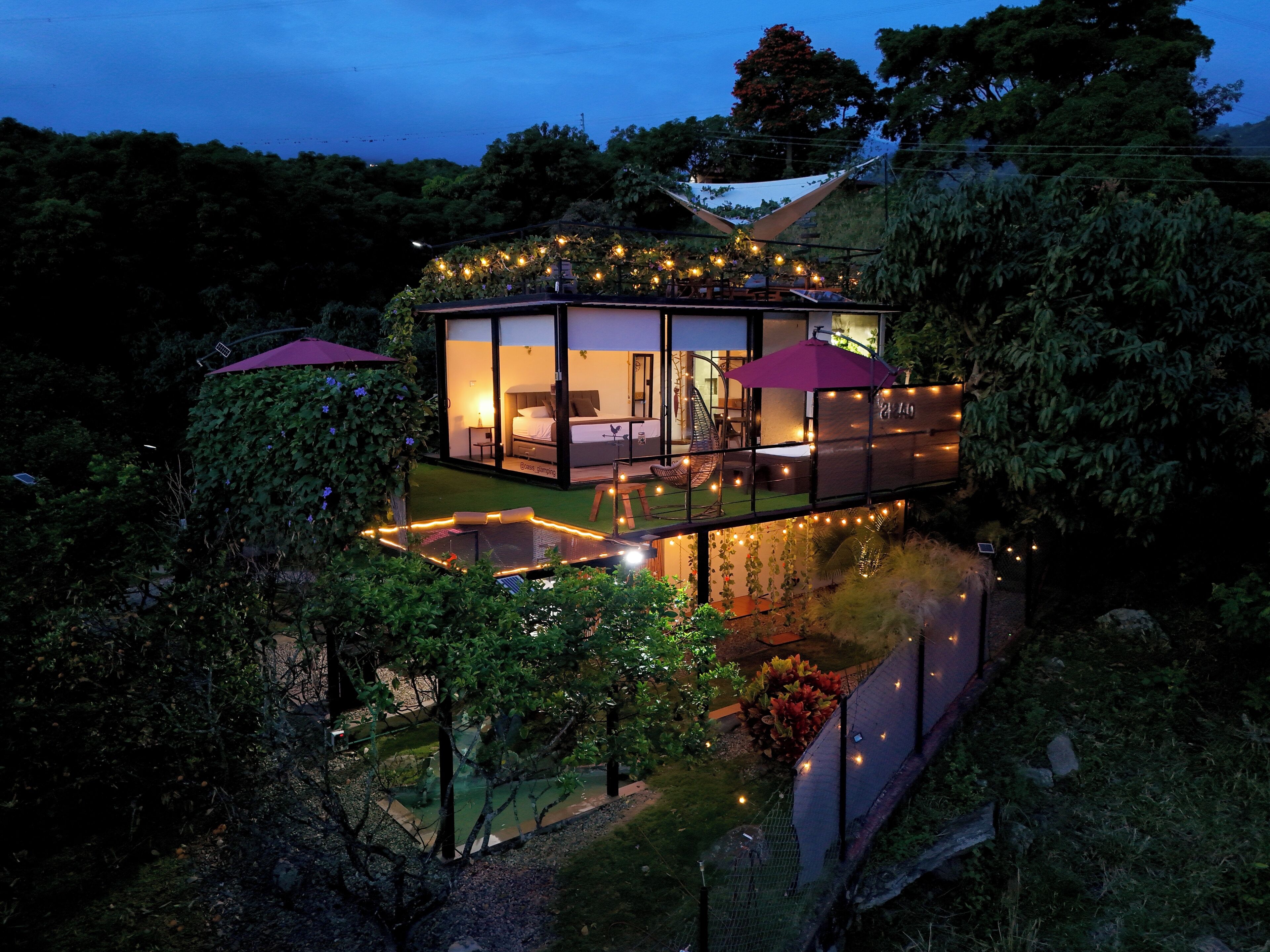 Uma casa moderna com fachada de vidro, varanda e área de jardim.