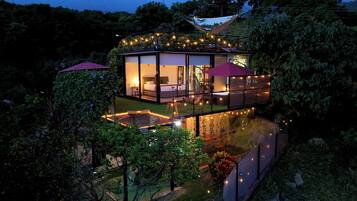 Uma casa moderna com fachada de vidro, varanda e área de jardim.