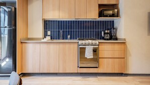 Uma cozinha moderna com armários de madeira, painel de fundo azul, forno de aço inoxidável e micro-ondas.