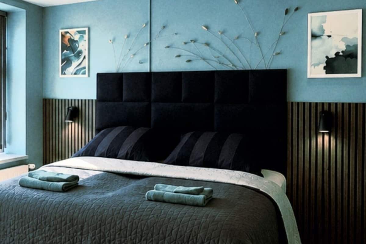 Quarto moderno com cama grande, cabeceira com ripas verticais e parede azul.