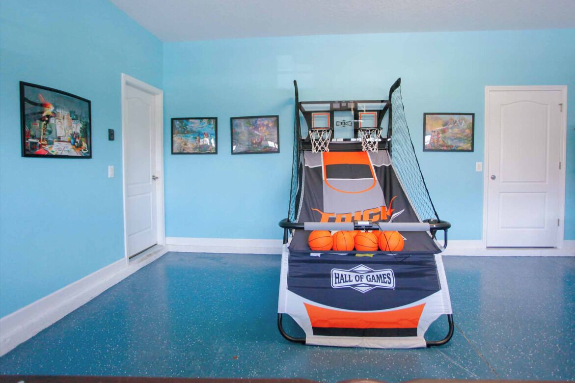 Quarto com cesto de basquete, cama com colcha temática 'Hall of Games' e duas portas.