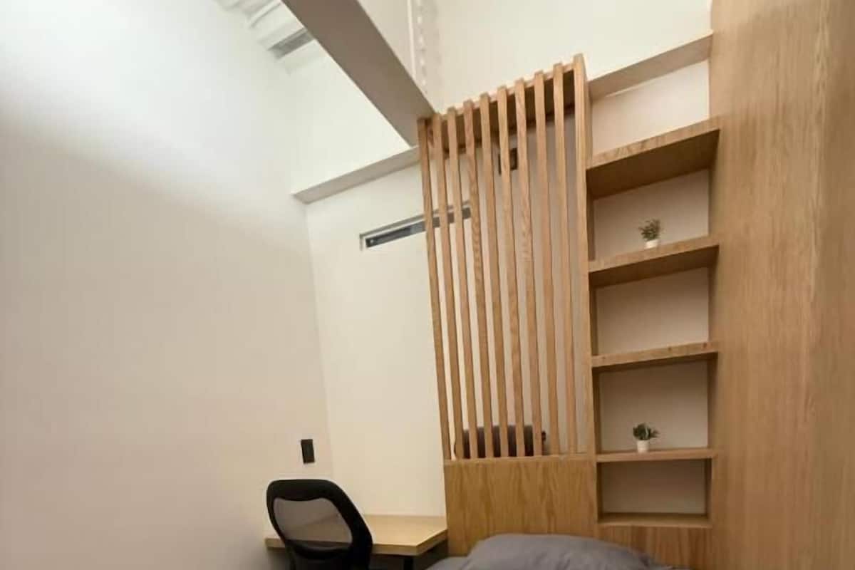 Quarto compacto com cama, escrivaninha e cadeira.