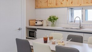 Uma cozinha moderna com armários de madeira, bancada branca e mesa de jantar com cadeiras.
