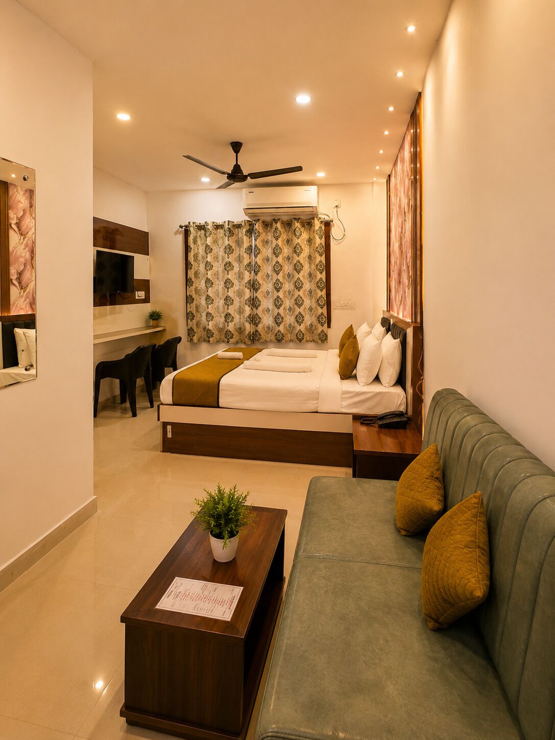 Quarto de hotel moderno com cama, sofá, escrivaninha e ventoinha no teto.