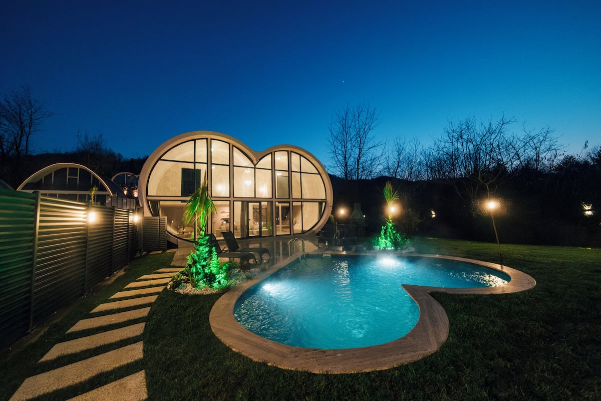 Uma casa moderna com piscina, janelas amplas e área externa bem iluminada.
