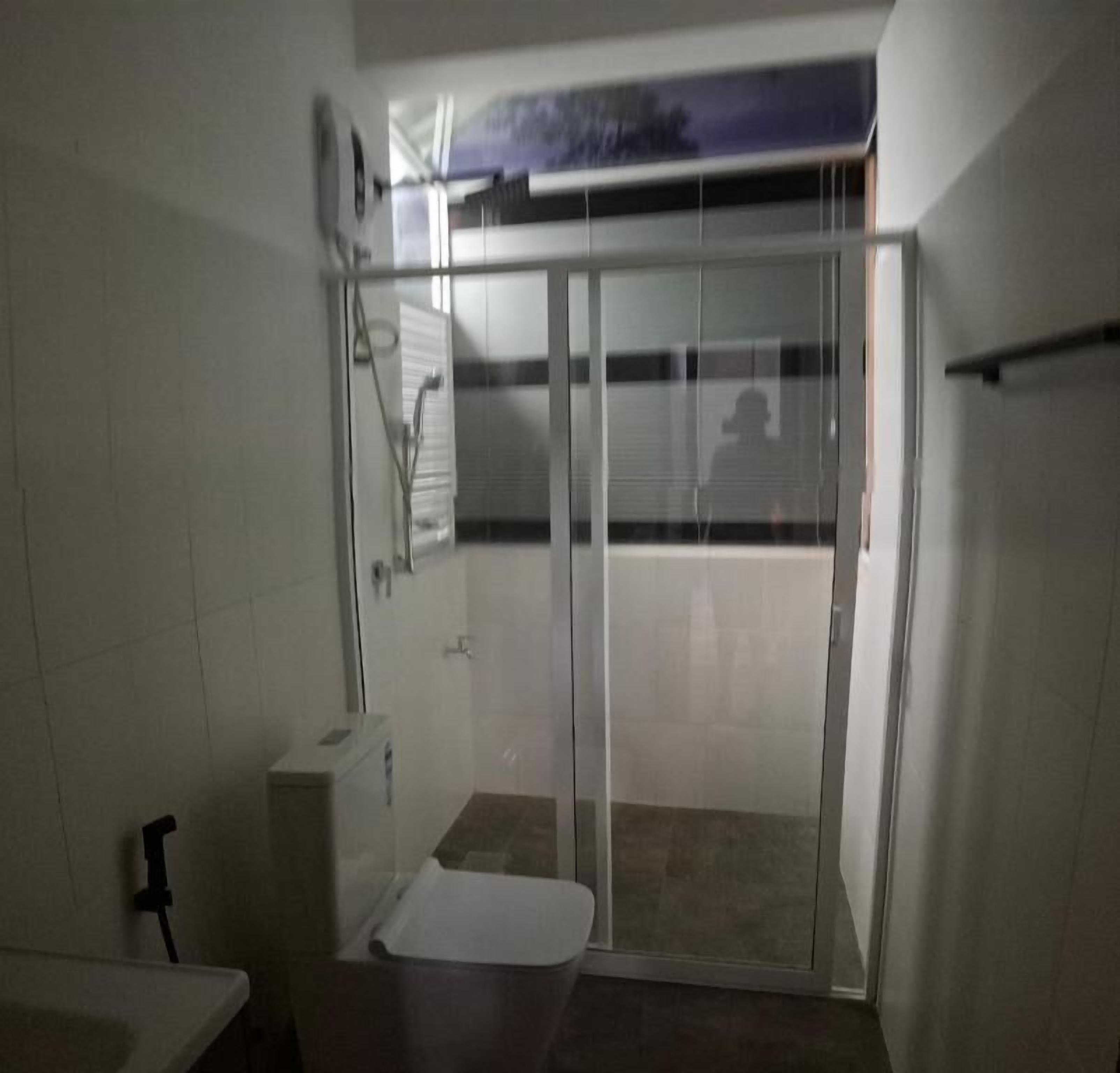 Casa de banho com sanita, chuveiro e porta de vidro que dá para uma varanda.
