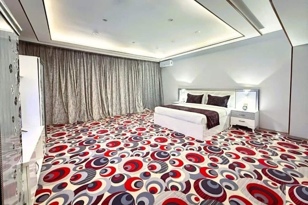 Quarto moderno com carpete estampado, uma cama, uma mesinha de cabeceira e um guarda-roupa.