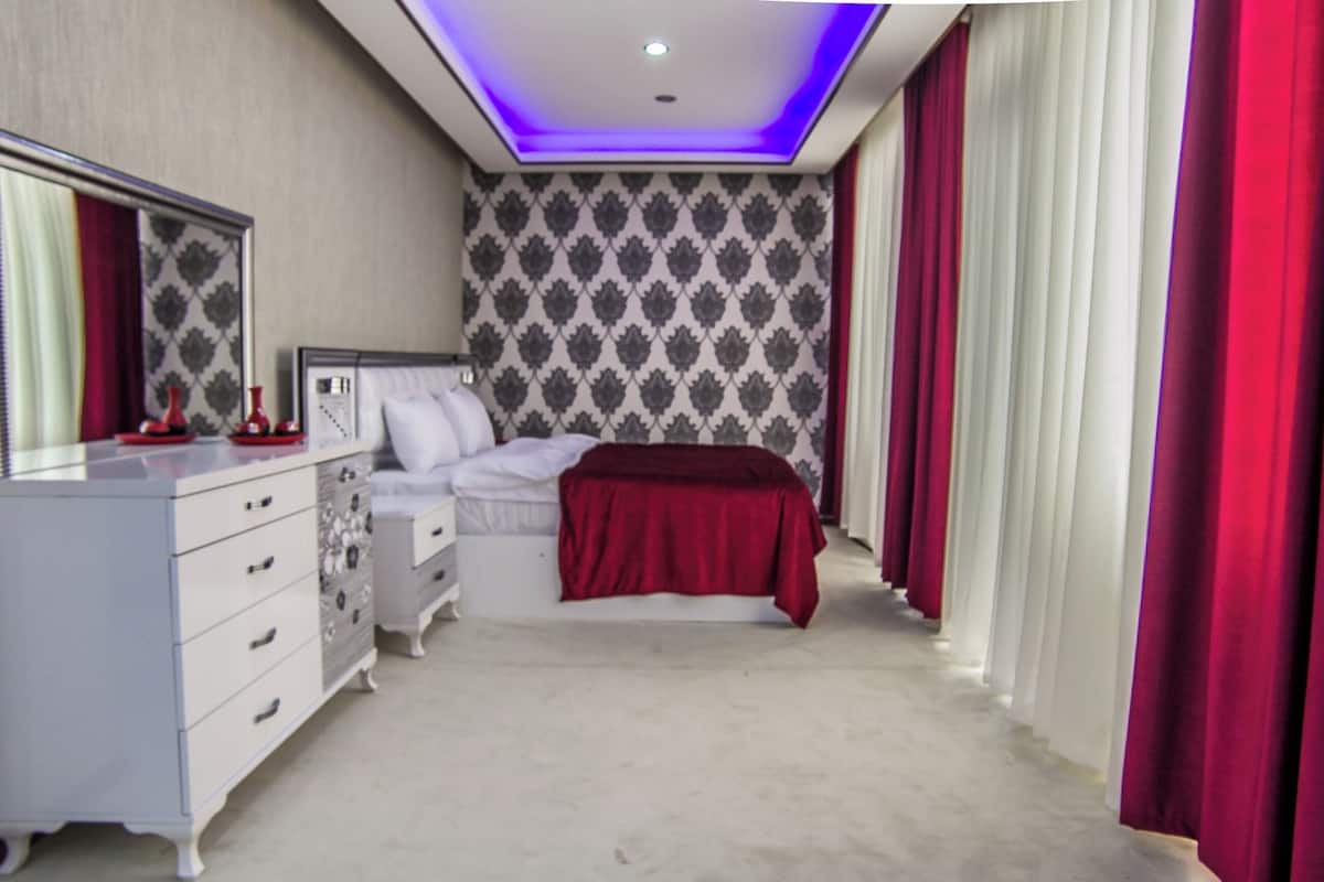 Quarto com cama, penteadeira, espelho e papel de parede estampado.
