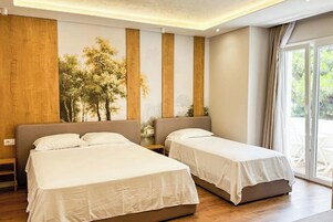 Quarto de hotel com duas camas, uma janela grande e vista para o verde lá fora.