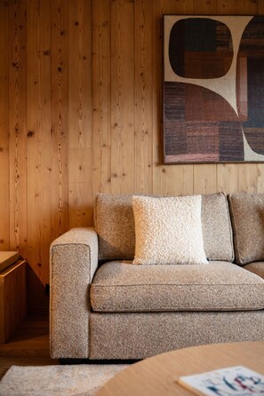 Um quarto com painéis de madeira, um sofá e uma grande pintura abstrata.