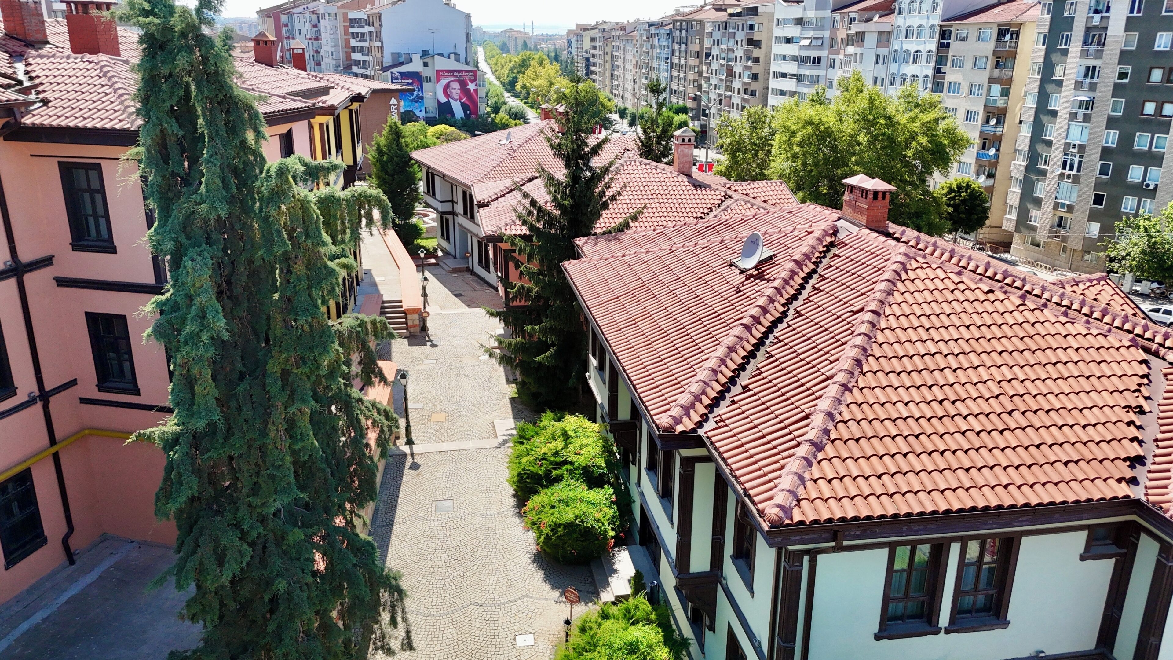 Uma rua estreita ladeada por edifícios tradicionais, alguns com telhados de terracota e outros com diferentes estilos arquitetônicos.