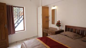 Quarto com cama, guarda-roupa, espelho, mesa de cabeceira e janela com vista para uma escada.