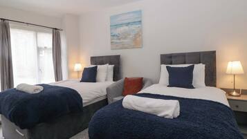 Quarto de hotel com duas camas, cada uma com cabeceira, luminárias e um quadro na parede.