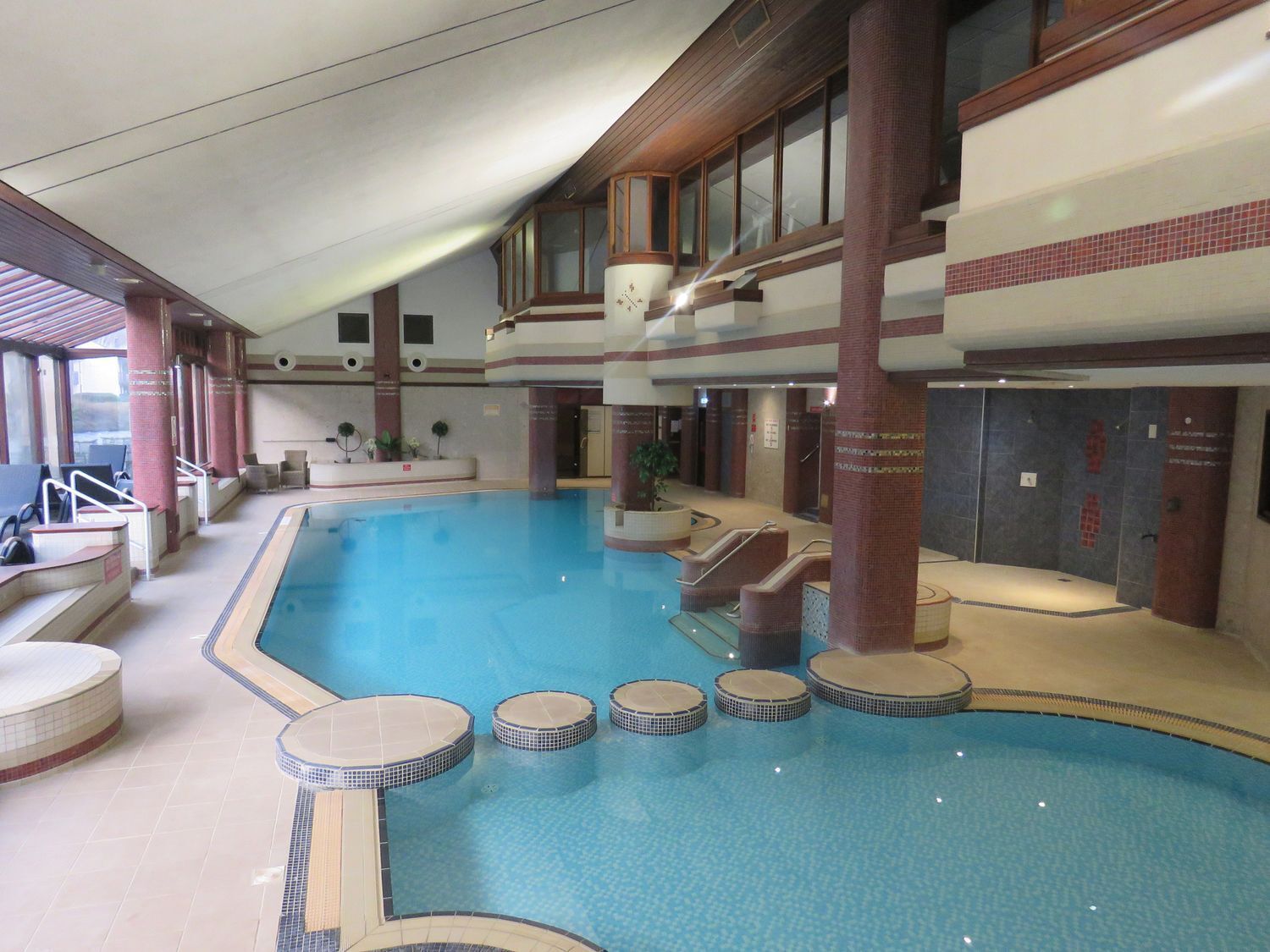 Piscina interior com vários níveis, áreas de estar e seção de spa.