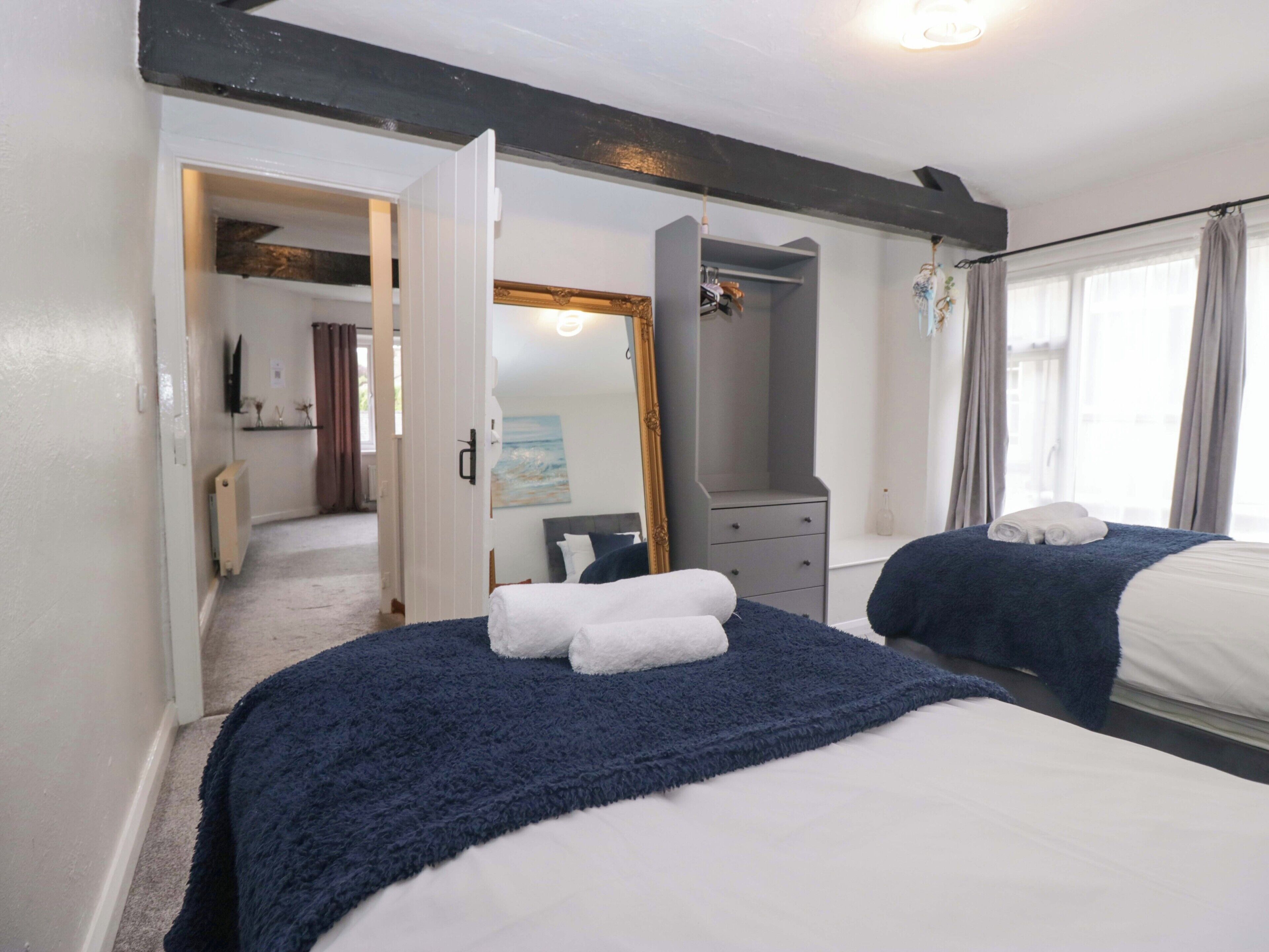 Quarto de hotel com duas camas, um closet espaçoso, um espelho e vista para o exterior.