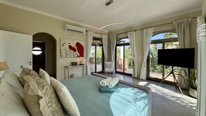 Um quarto espaçoso com uma cama grande, televisão de tela plana e vista para o exterior.