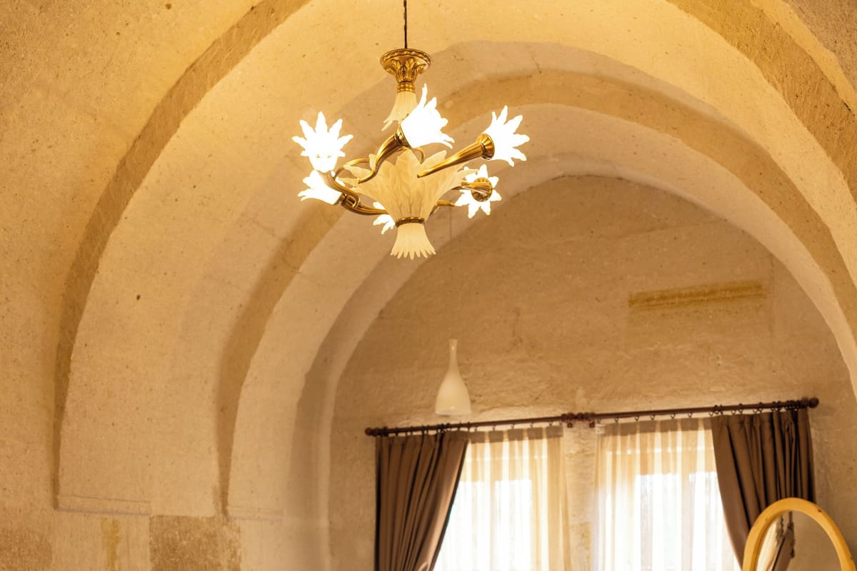 Um quarto com cama, poltrona, banheira, espelho e lustre.