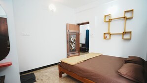 Quarto com cama de madeira, guarda-roupa com padrão floral e prateleira na parede.