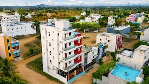 Um edifício residencial com várias andares, varandas, piscina e vista para os arredores.