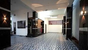 Corredor com piso estampado, balcão de recep ção e luminária fixada na parede.