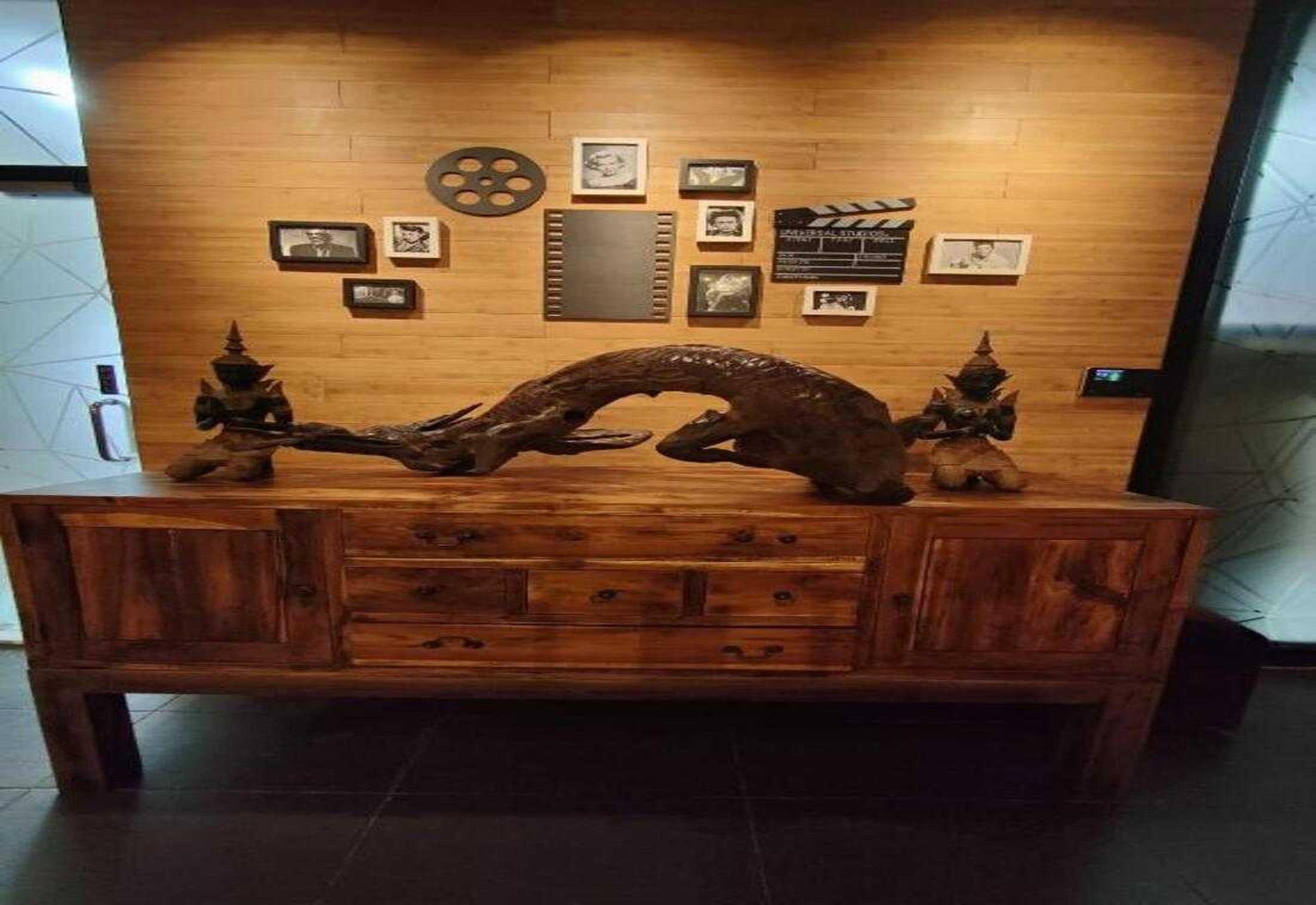Um balcão de madeira na recepção, com uma grande escultura curva no centro, acompanhada por duas esculturas menores.